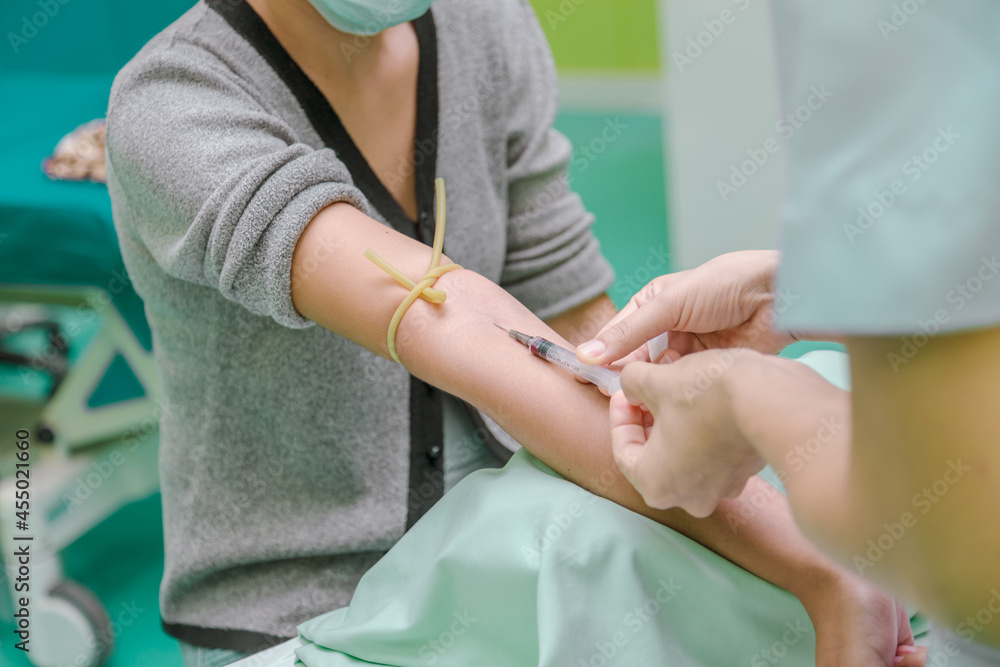 A health worker taking a blood sample from the vein by piercing the ...