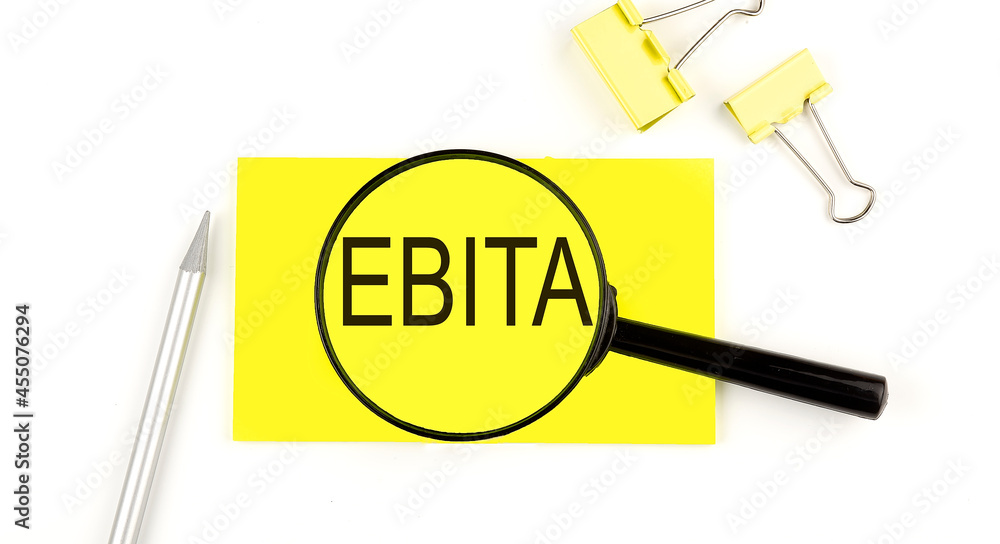 EBITA text on the sticker through magnifier. View from above. Business ...
