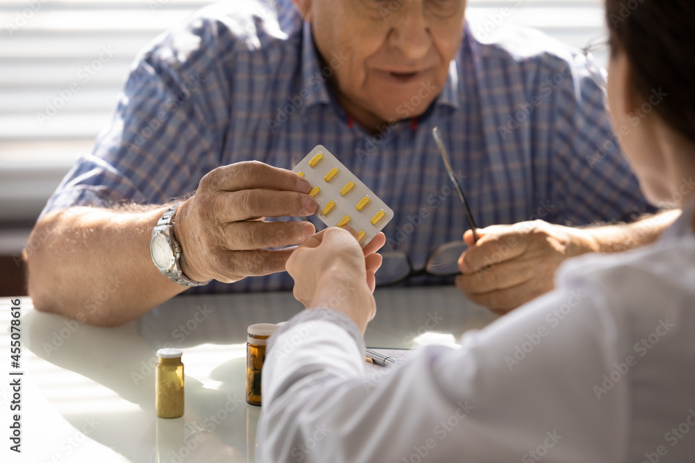 Female GP doctor giving pills to older male patient at appointment ...