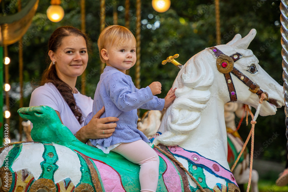 Cute baby girl with mother on the horse of old retro carousel, Prague, Czech republic Stock ...