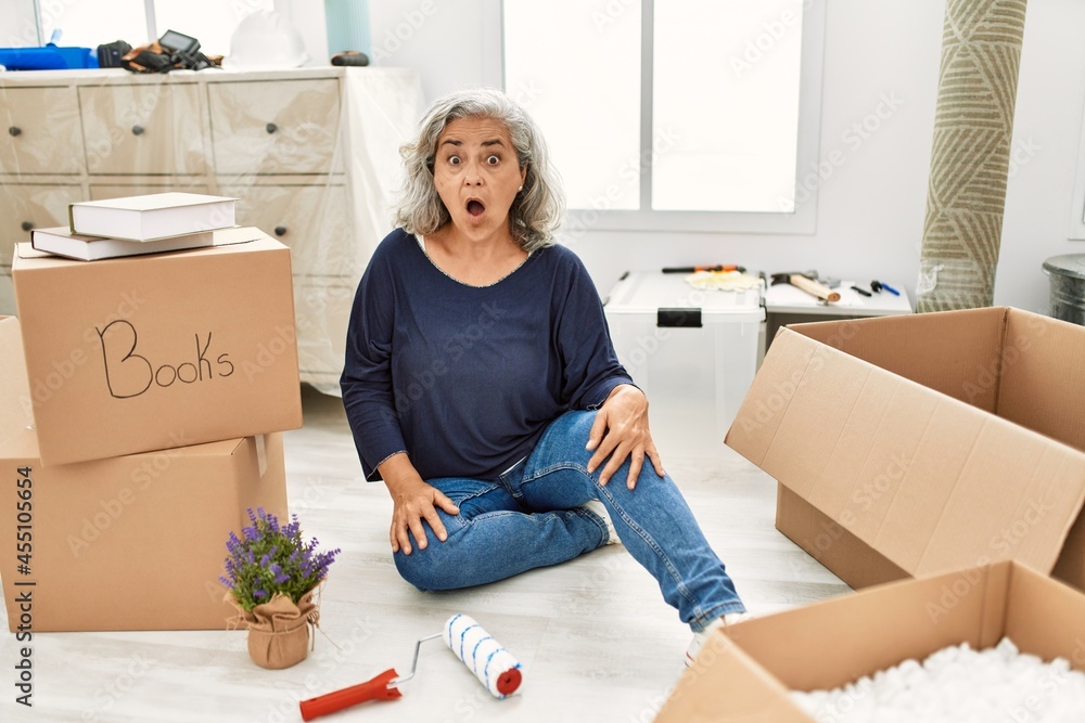 Middle age woman with grey hair sitting on the floor at new home scared ...