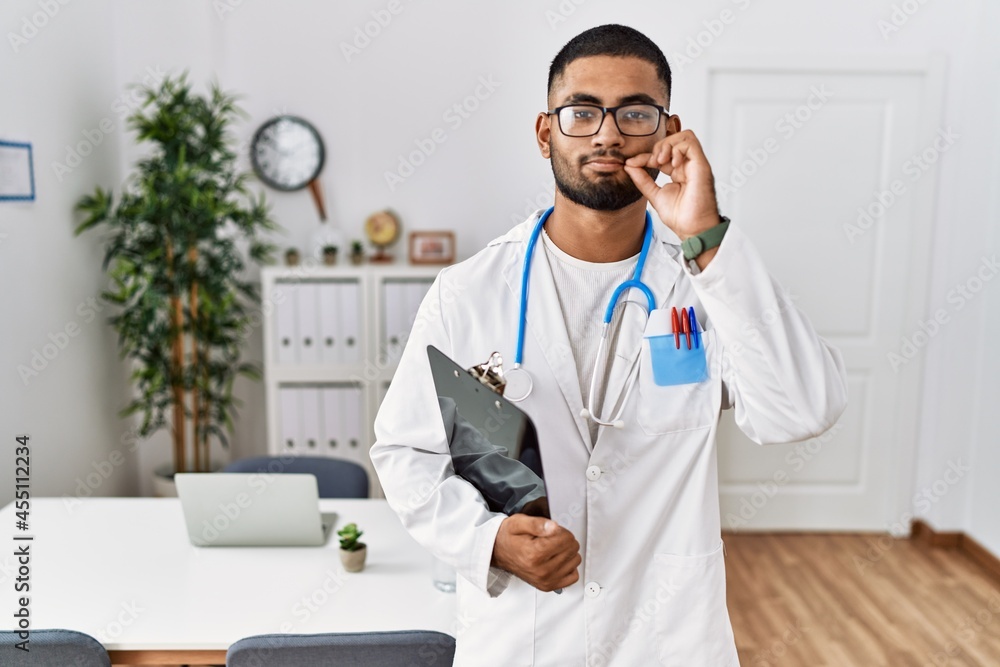 Young indian man wearing doctor uniform and stethoscope mouth and lips ...