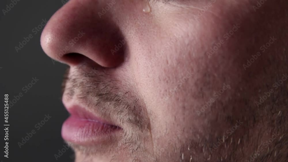 Close up of the eye cheek of a young man with a tear running down her ...