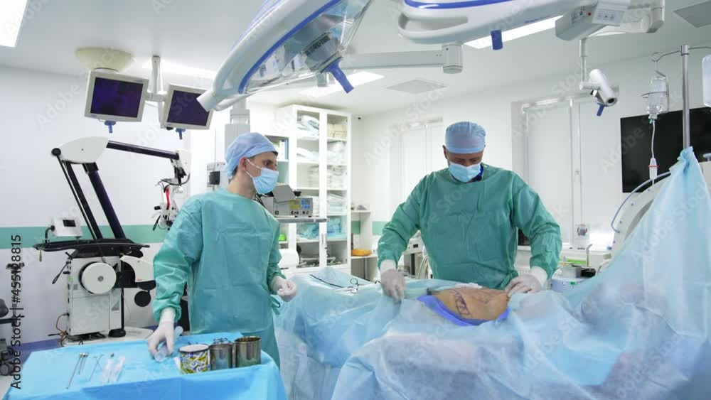 Surgeon and assistant are performing surgery on belly. Liposuction ...