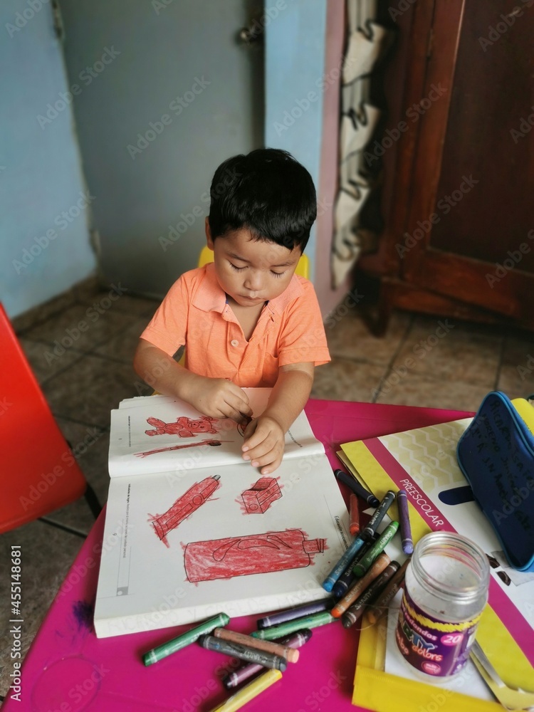 Child paints his pictures, child colors in his picture book, sitting ...