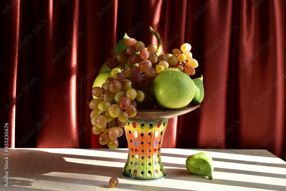 still life with pink grapes, green apples and figs on a burgundy ...