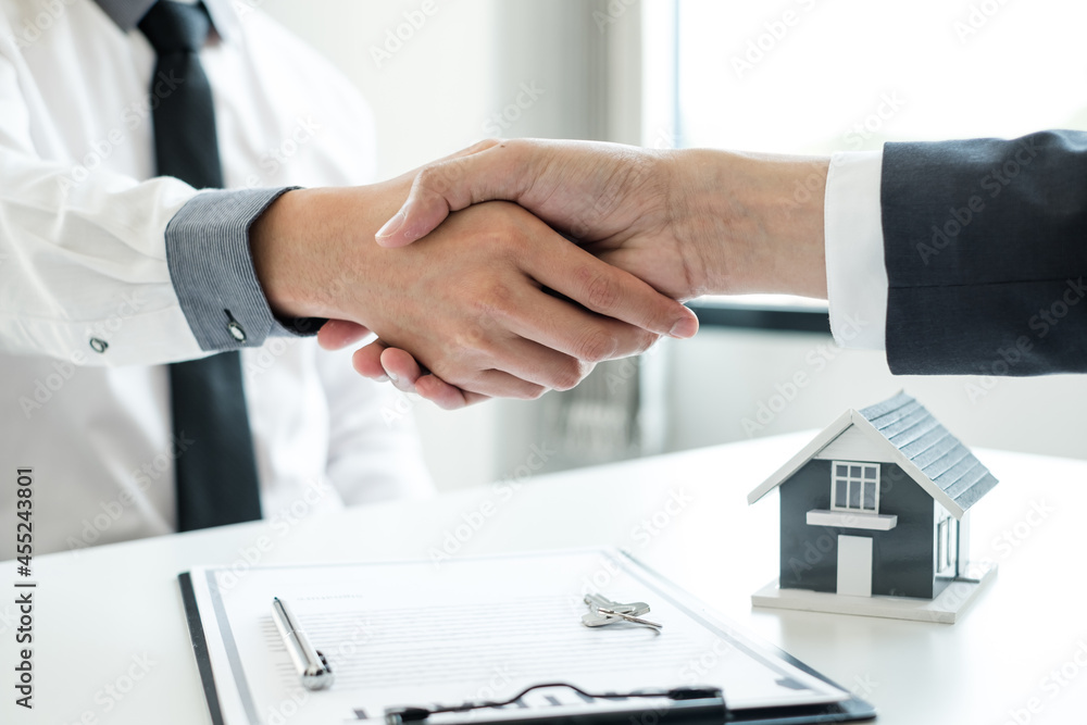 Businessmen and brokers' real estate agents shake hands after ...