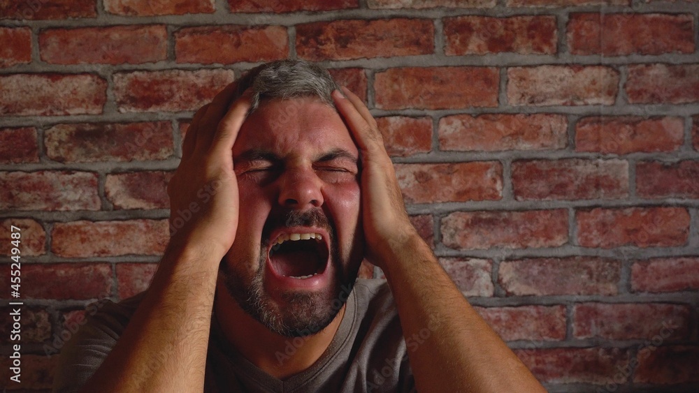 The man screams in grief. Stress. Powerful emotions. Tears the hair on ...