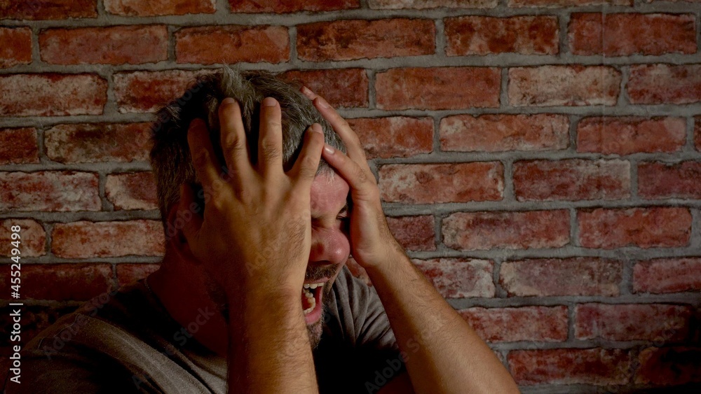 The man screams in grief. Stress. Powerful emotions. Tears the hair on ...