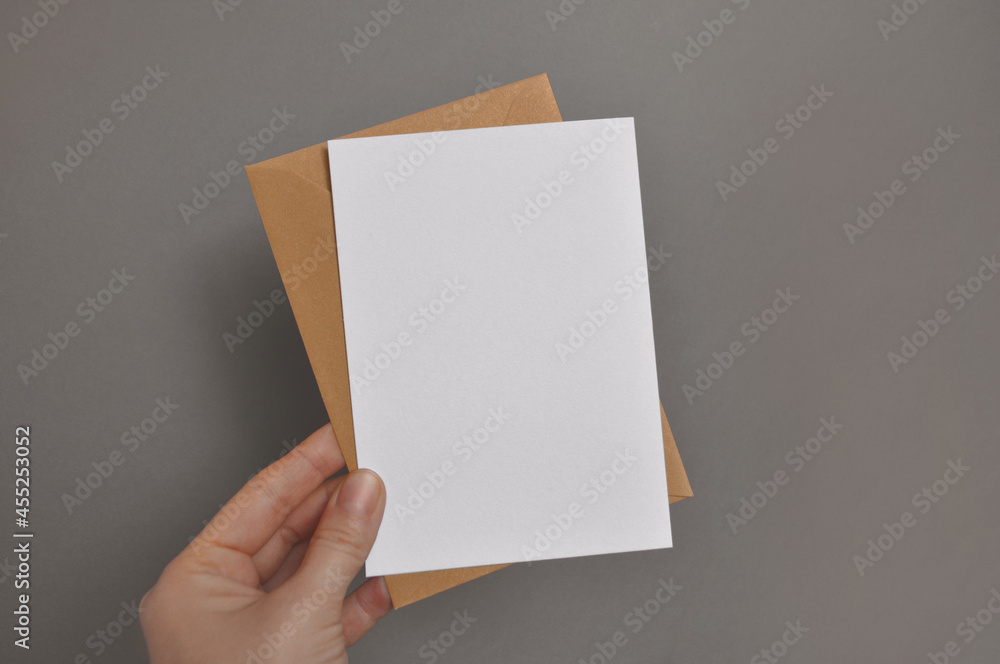 hand holding blank card with craft envelope on grey background ...