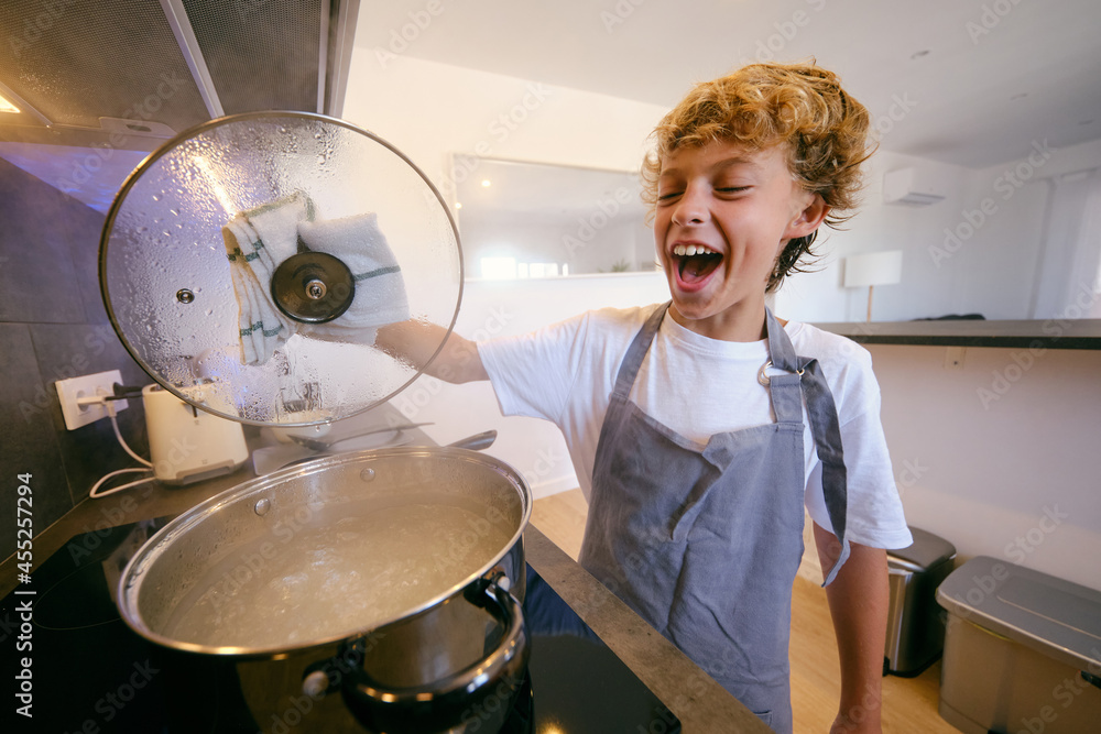 Excited boy with lid against boiling water in pot Stock Photo | Adobe Stock