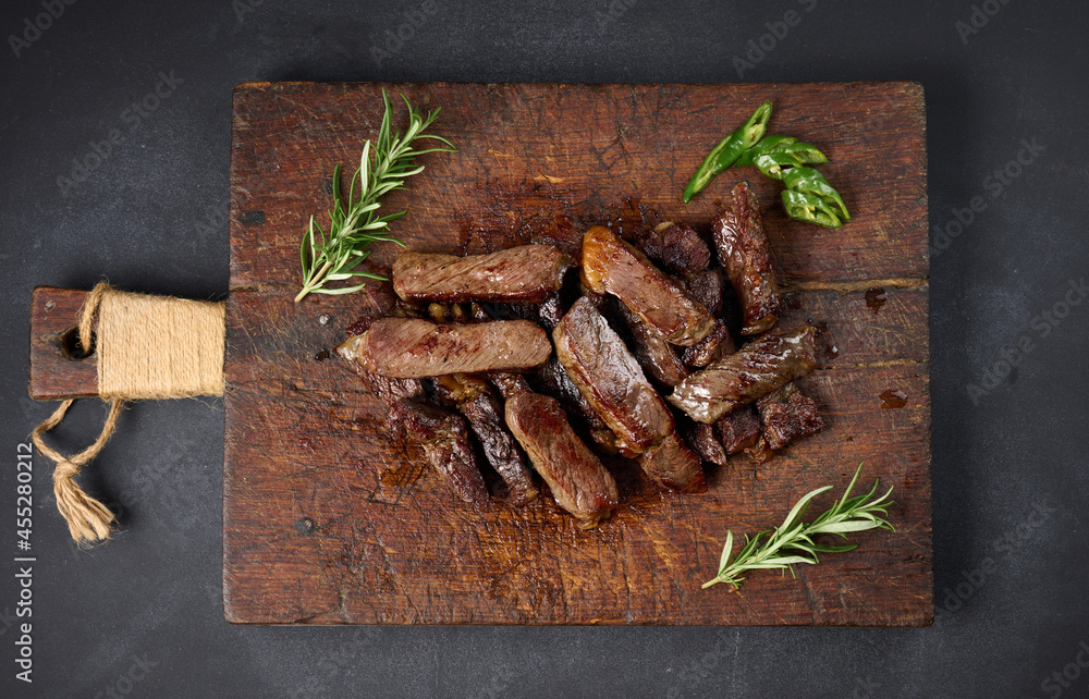 roasted piece of beef ribeye cut into pieces on a vintage brown ...