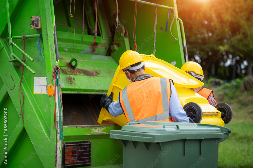 Rubbish cleaner man working with green garbage truck loading waste and ...