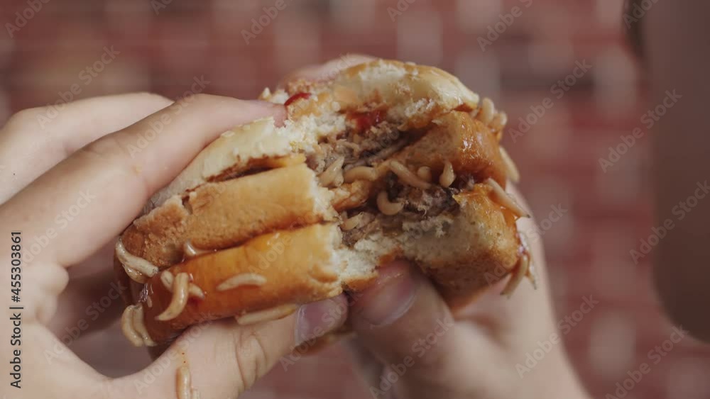 Man eats juicy fresh burger full of maggots. Closeup of man eating ...