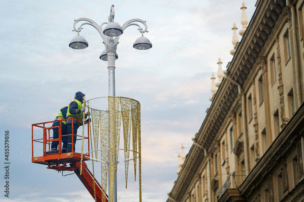 Workers in lift bucket decorating street lamp. Outdoor Workers ...