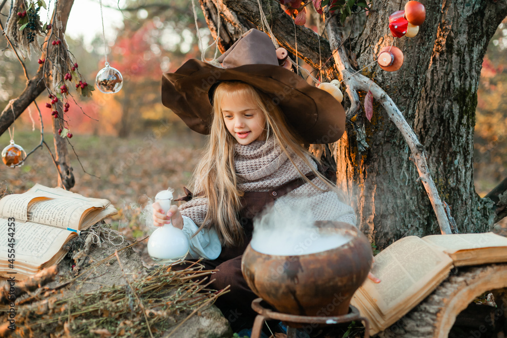 Happy Halloween. A cute girl in a witch costume is in the witch's den ...