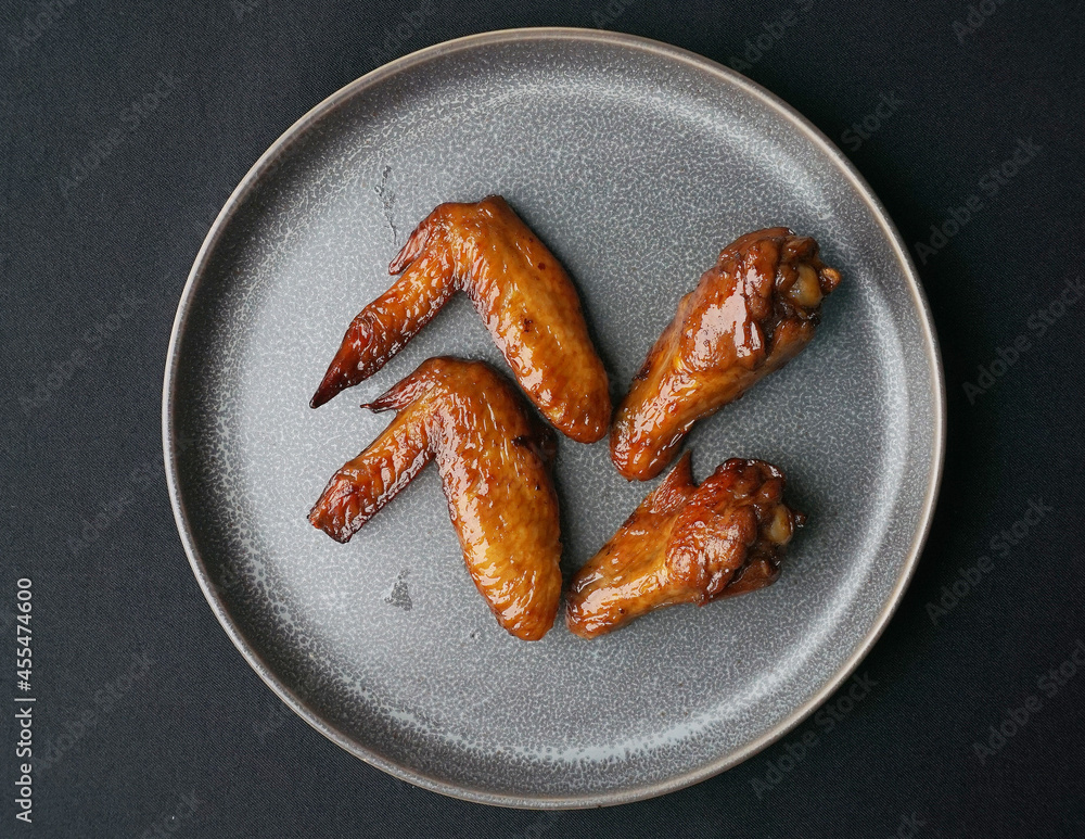 local charcoal bbq grilled honey golden chicken wing in plate on dark ...