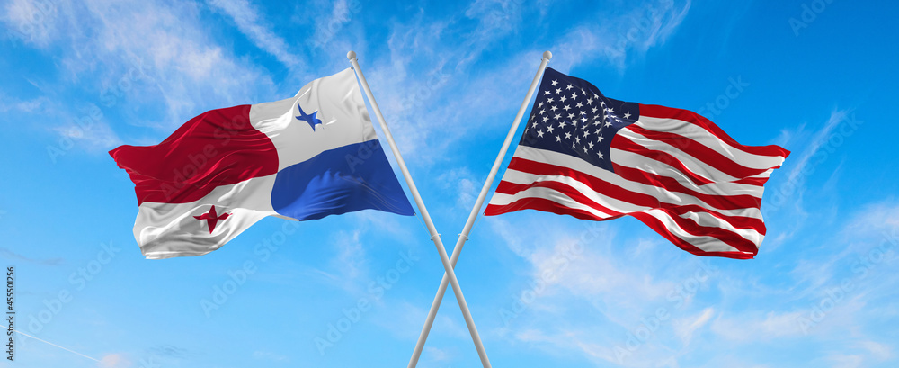 flags of USA and Panama waving in the wind on flagpoles against the sky ...