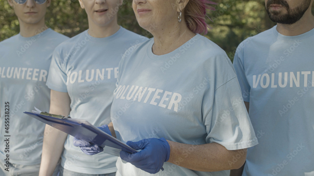 Group of volunteers ready to perform task, senior woman giving ...