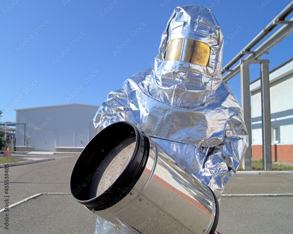 A firefighter in a shiny heat-reflecting suit and a fireman's barrel in ...