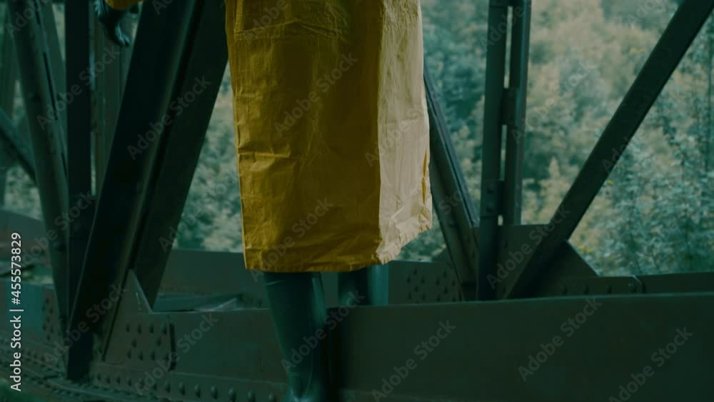 man in rubber boots, protective suit, gas mask walks over an iron ...