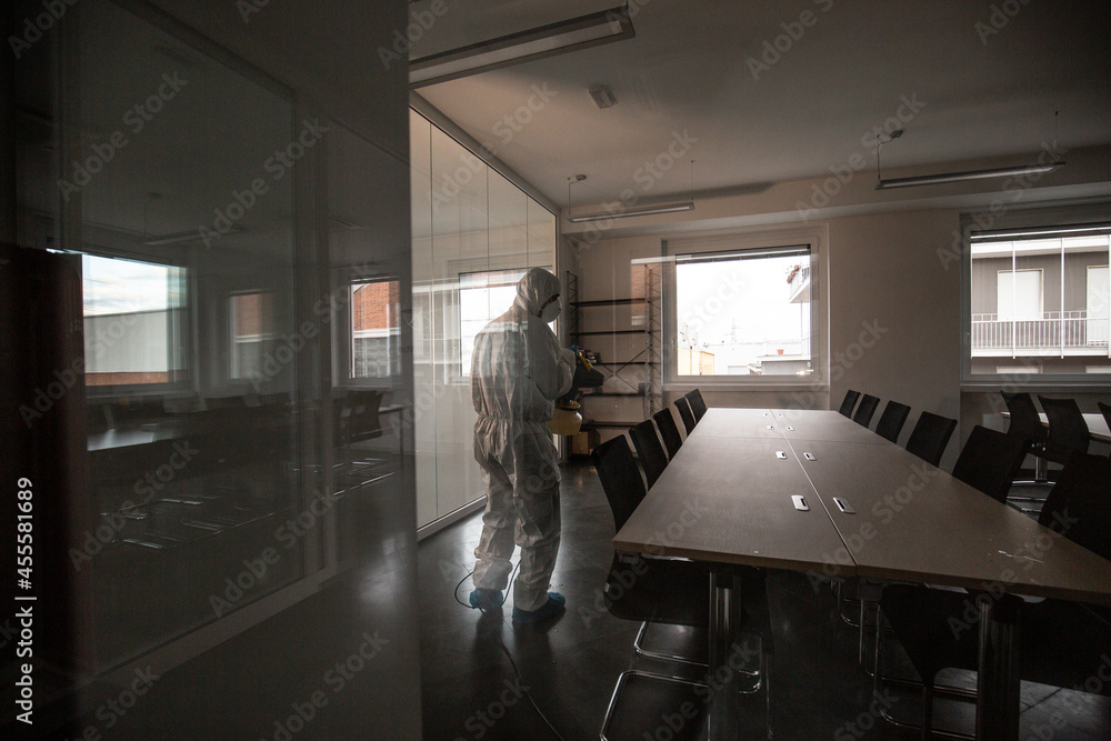 Man in PPE sanitizing a meeting room in an office Stock Photo | Adobe Stock