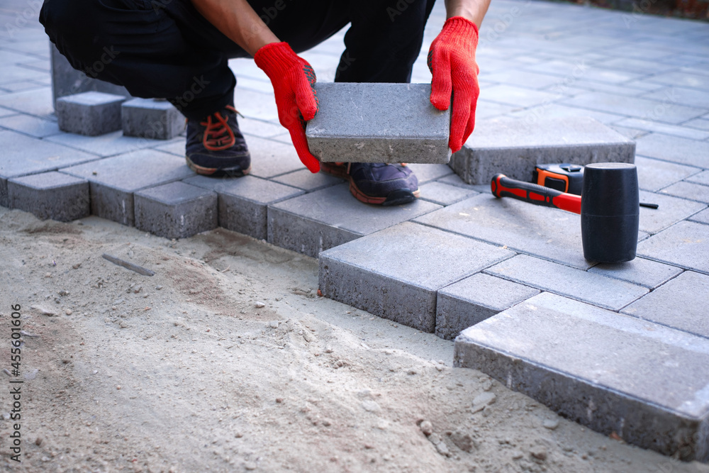 The master in yellow gloves lays paving stones in layers. Garden brick ...