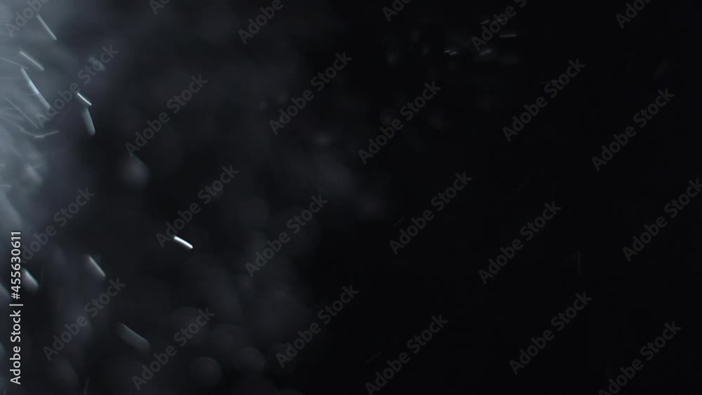 White particles in the air on a black background. Some of the particles ...