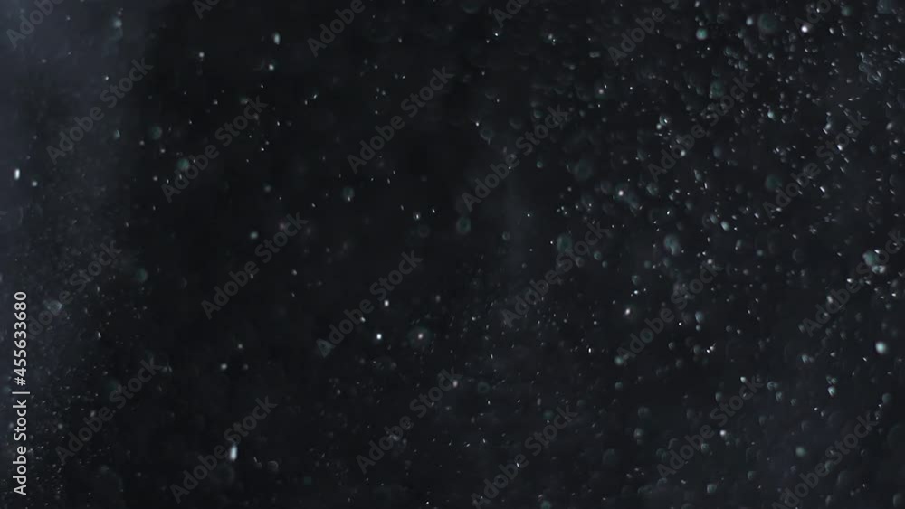 Vidéo Stock A suspension of white-silver particles in the air on a black background. Some of the ...