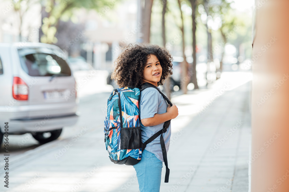 Afro handsome boy walks with his backpack in the park after school ...