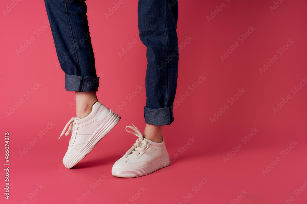 inverted female legs in white sneakers pink background cropped view ...