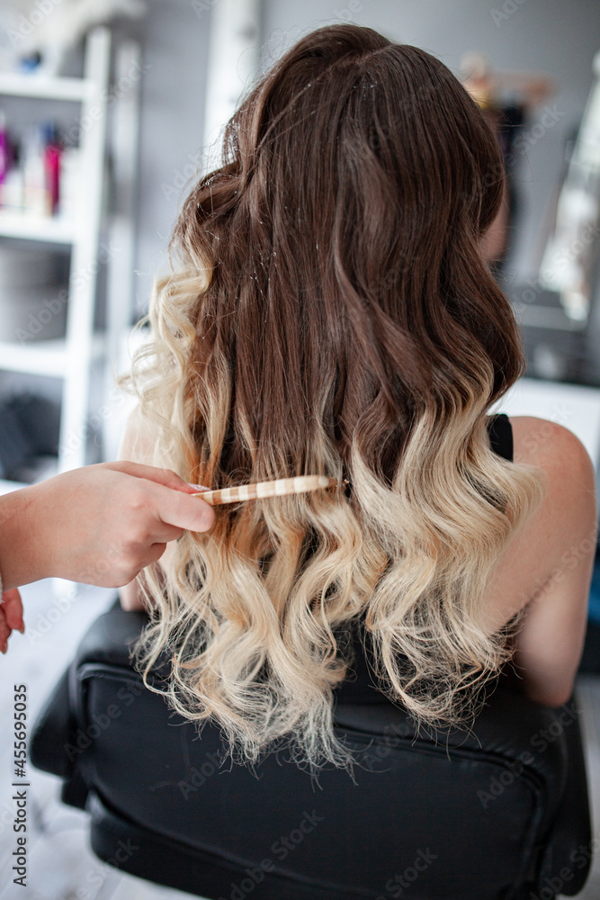 stylist hairdresser makes a hairstyle for a girl in his beauty salon ...