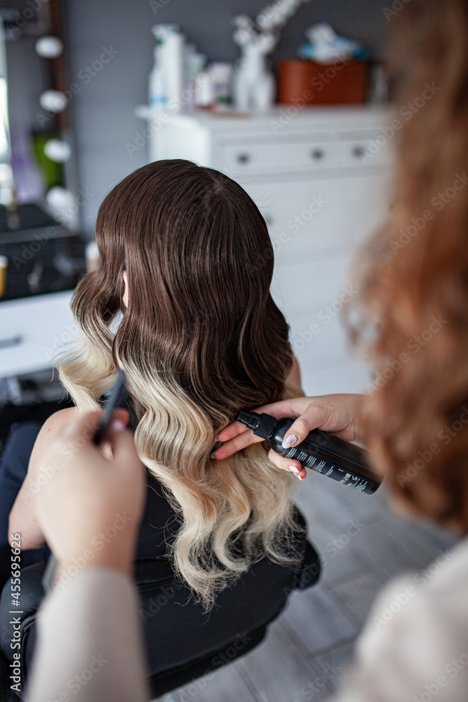 stylist hairdresser makes a hairstyle for a girl in his beauty salon ...