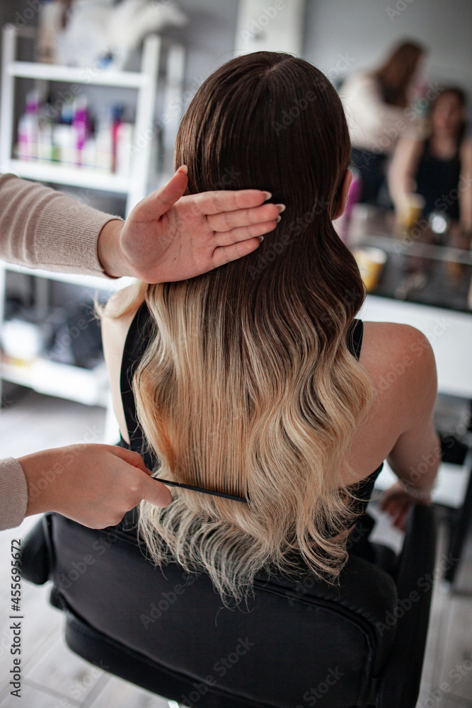 stylist hairdresser makes a hairstyle for a girl in his beauty salon ...