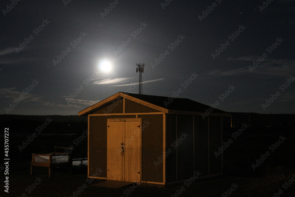 View of a farm shed and planter boxes by moonlight. Cell tower in the ...