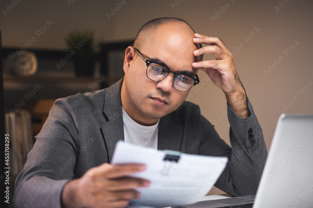 Young asian businessman working with laptop computer in the dark office ...