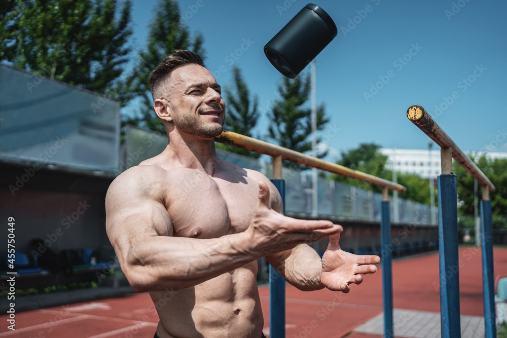 muscular athlete man throw up black container with protein whey powder ...