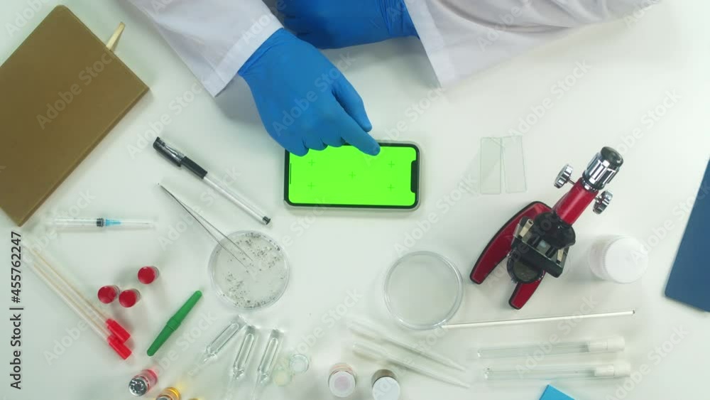 Doctor working in modern laboratory, using smartphone. Nurse typing in ...