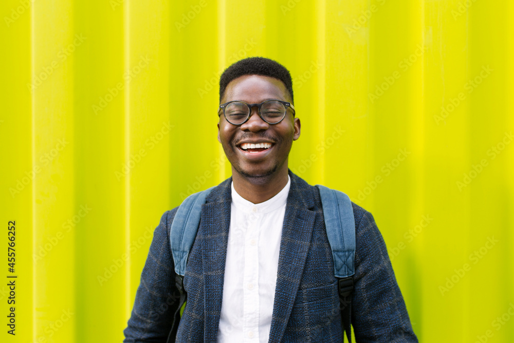 Cheerful outdoor portrait of a young black male against yellow ...