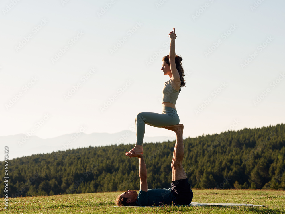 Calm Couple Practicing Acro Yoga Easy Throne Pose In Nature Stock Photo