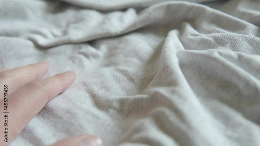Male hand checks the quality of fabric, grey cotton in a store or at a ...