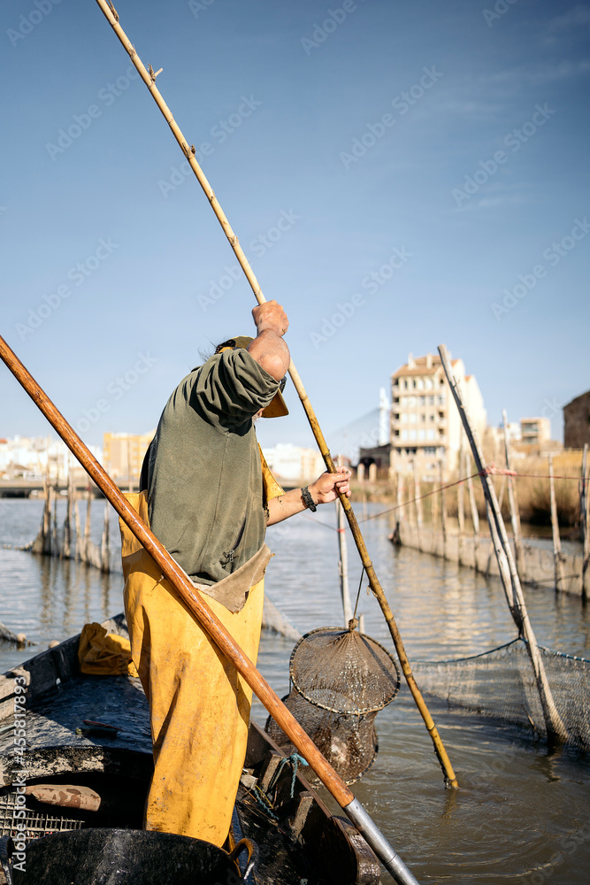Fisherman inserting a long bamboo pole with his fishing net into the ...