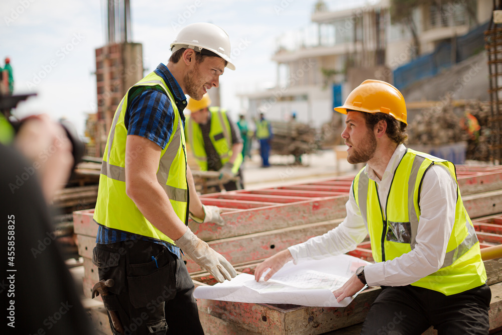 Construction worker engineer reviewing blueprints at highrise ...