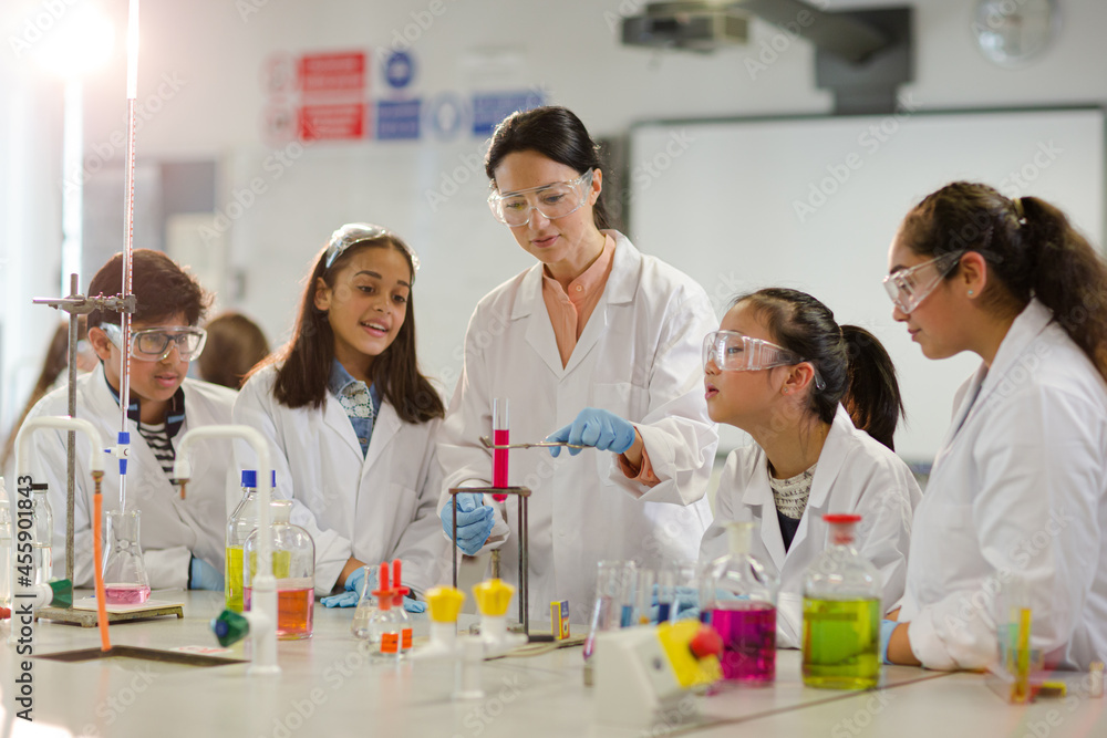 Female teacher and students conducting scientific experiment, watching ...