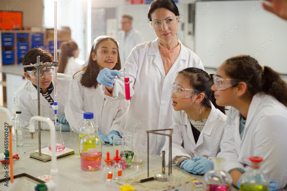 Female teacher and students conducting scientific experiment, watching ...