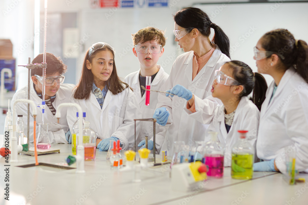 Female teacher and students conducting scientific experiment, watching ...