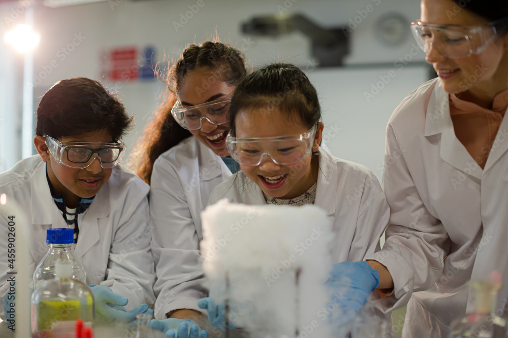 Female teacher and students watching scientific experiment chemical ...