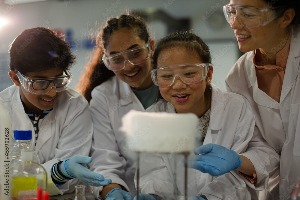 Female teacher and students watching scientific experiment chemical ...