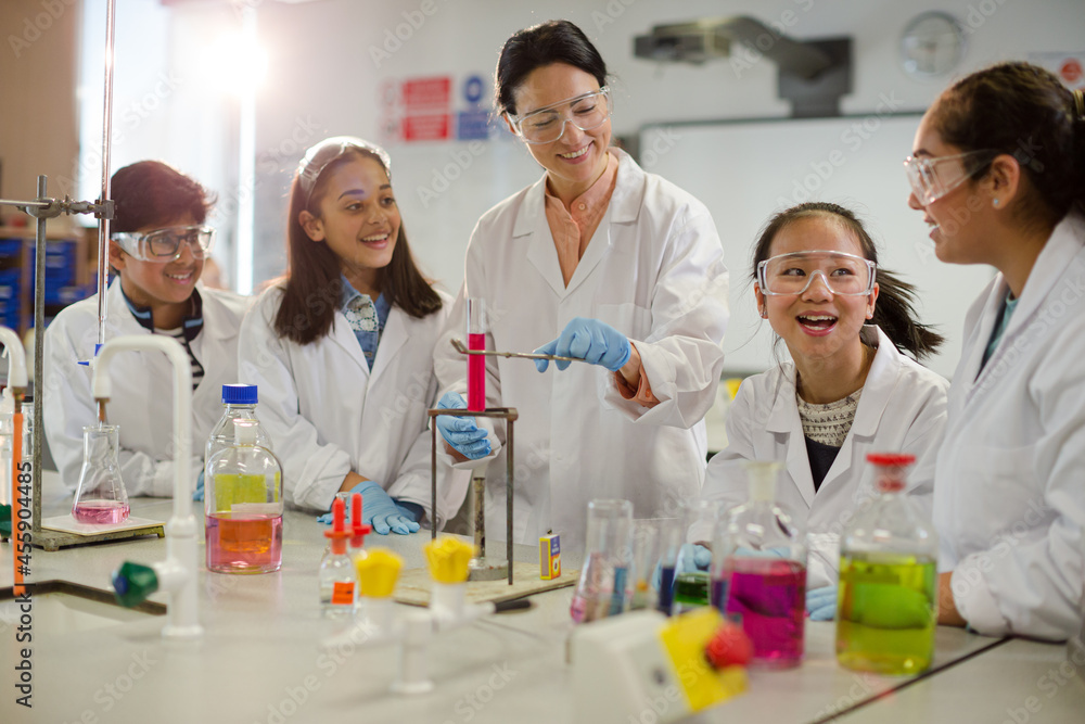 Female teacher and students conducting scientific experiment, watching ...
