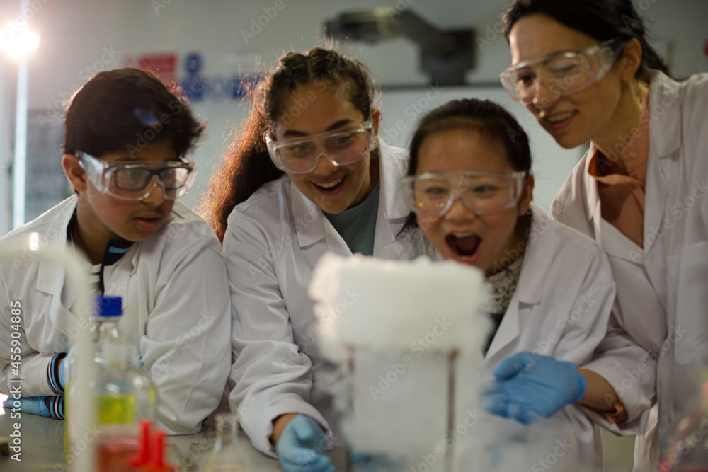 Female teacher and students watching scientific experiment chemical ...
